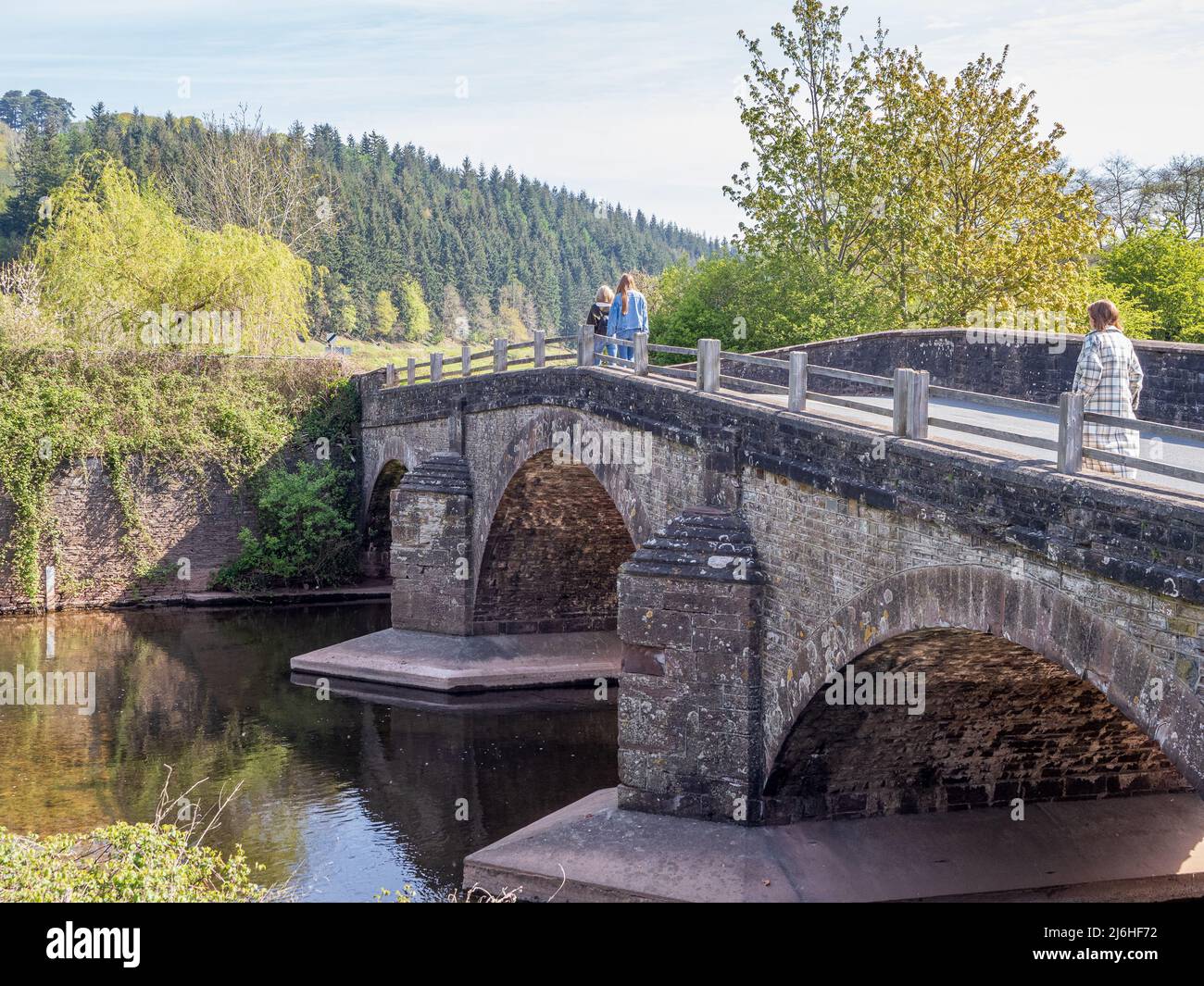 three people walking across a three arch medieval stone bridge in the ...