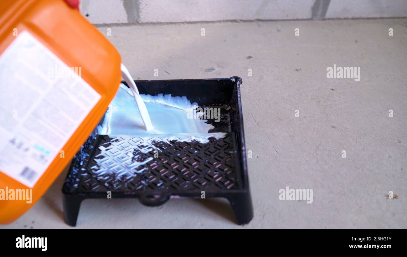 The primer is poured from an orange canister. The plasterer pours the ...