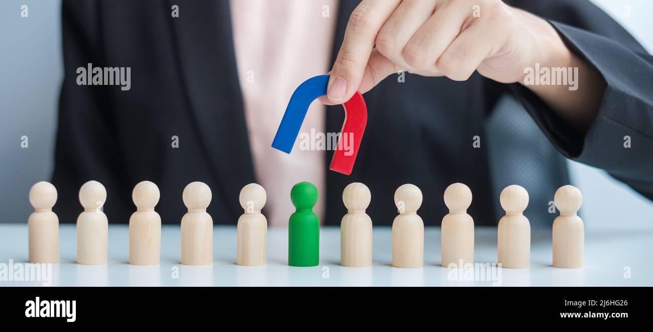 Business woman hand holding magnet and pulling man wooden figure from ...