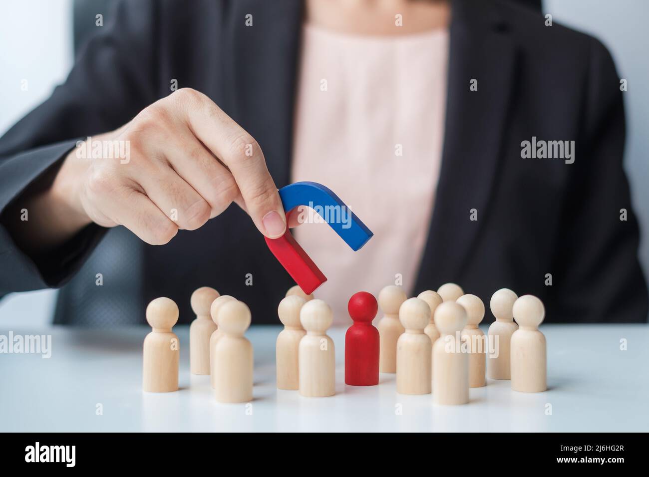 Business woman hand holding magnet and pulling man wooden figure from ...