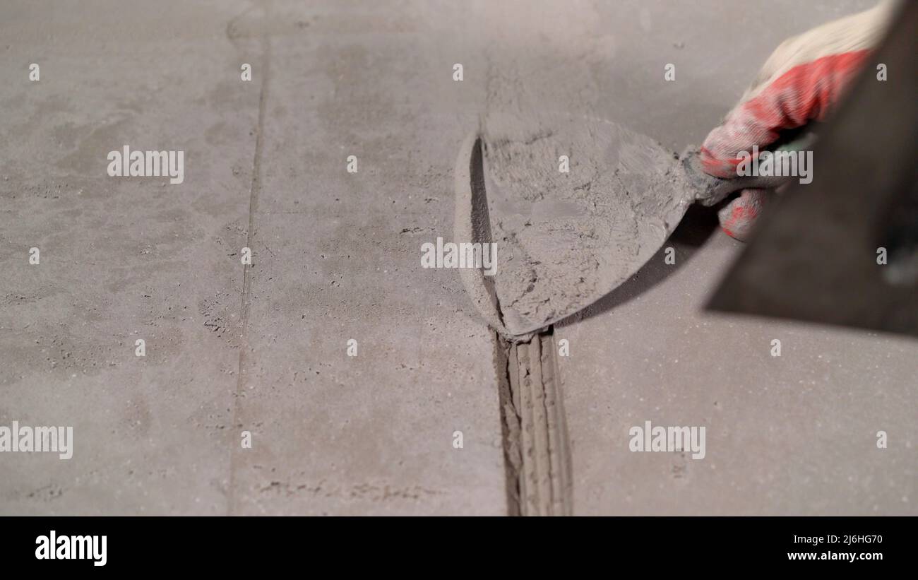 The worker is filling the cracks with plaster. Close-up of a hand with ...