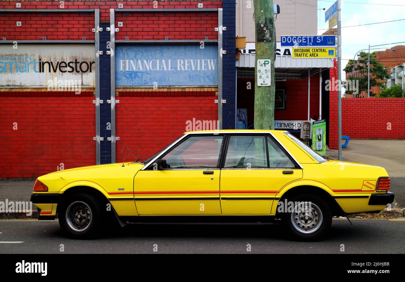 Bright yellow vintage Ford Falcon S car parked on a rundown city street ...