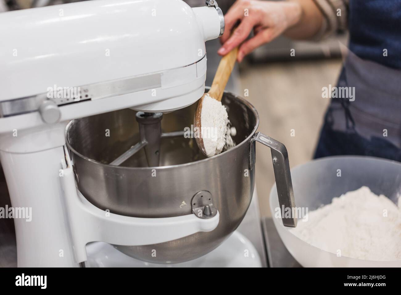 Woman adding flour with wooden spoon into mixture in blender Stock ...