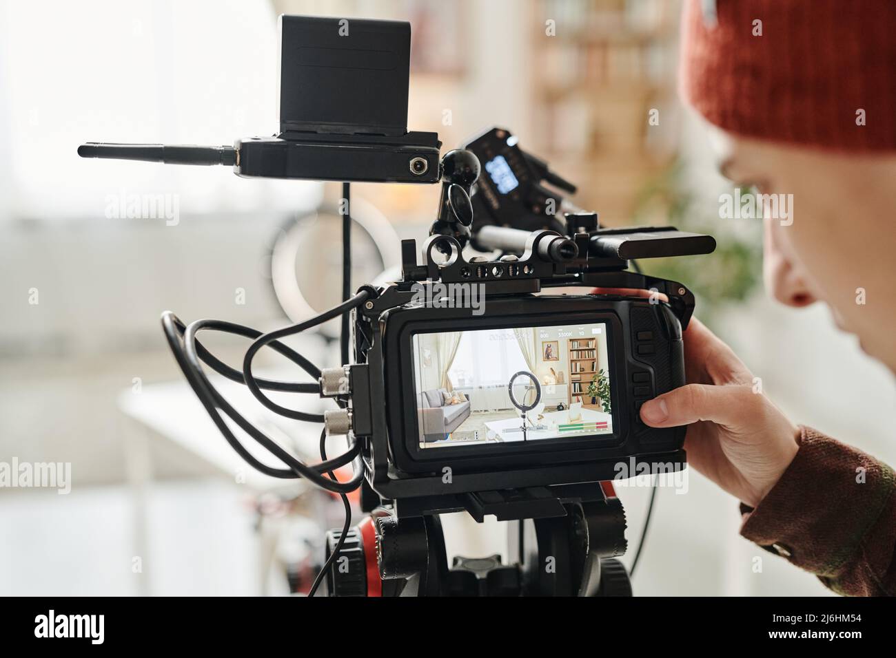 Screen of camera and hand of cameraman standing in spacious living room ...