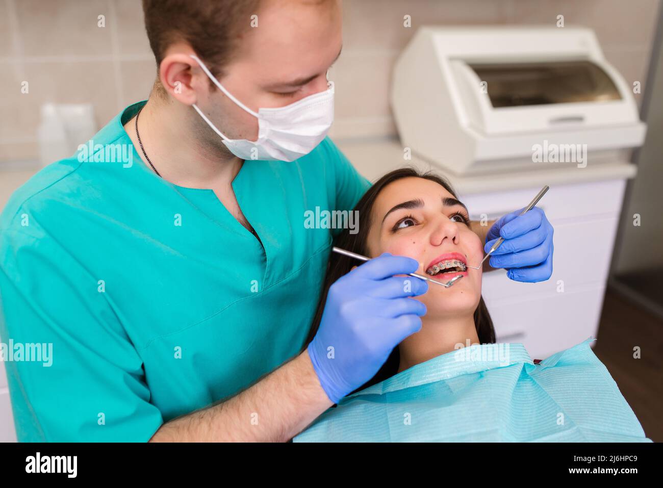 A male dentist examines a patient's teeth using a professional dental ...