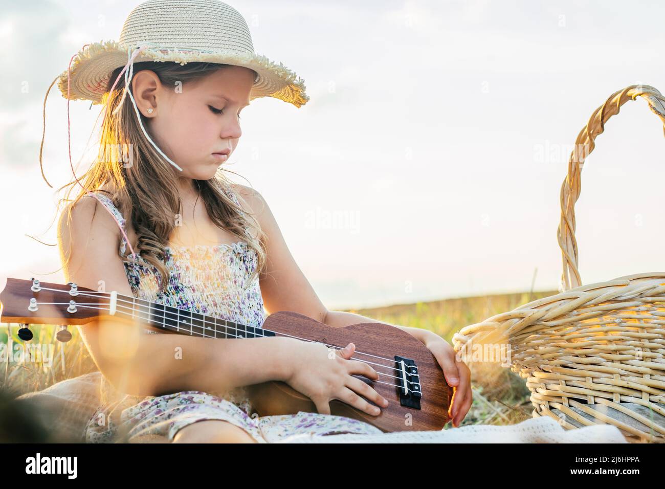 Portrait of girl sitting on blanket in dry hay field, having picnic ...
