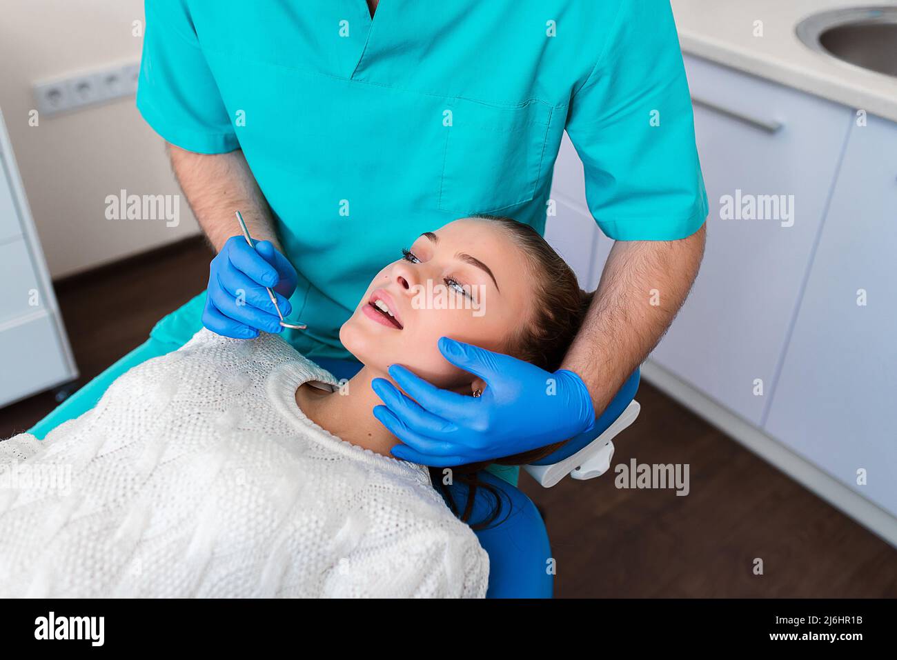 Pretty young woman sitting in dental chair at medical center while ...