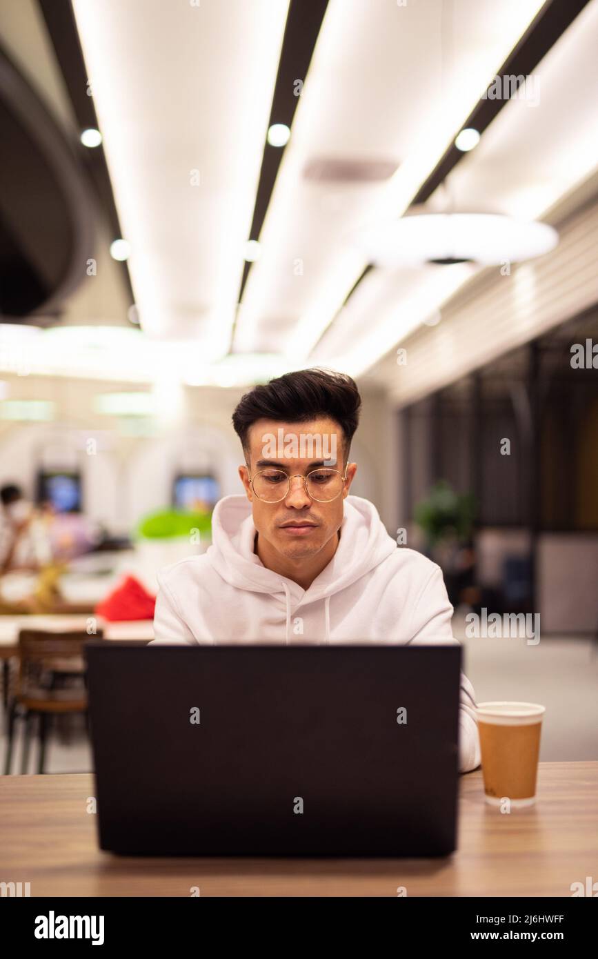 Portrait of handsome young cool stylish man using laptop at coffee shop ...