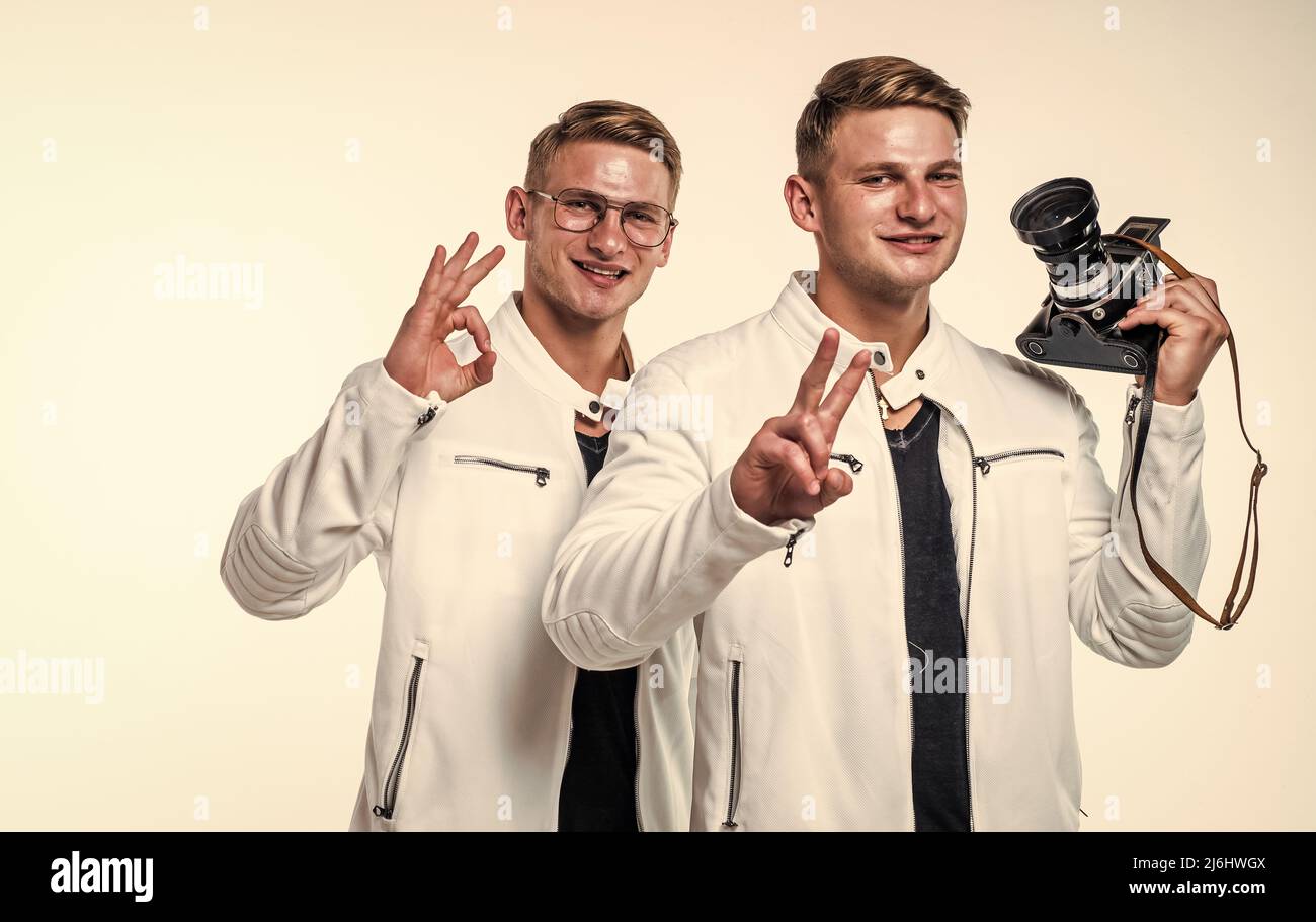 young twin brothers with similar appearance use retro photo camera ...