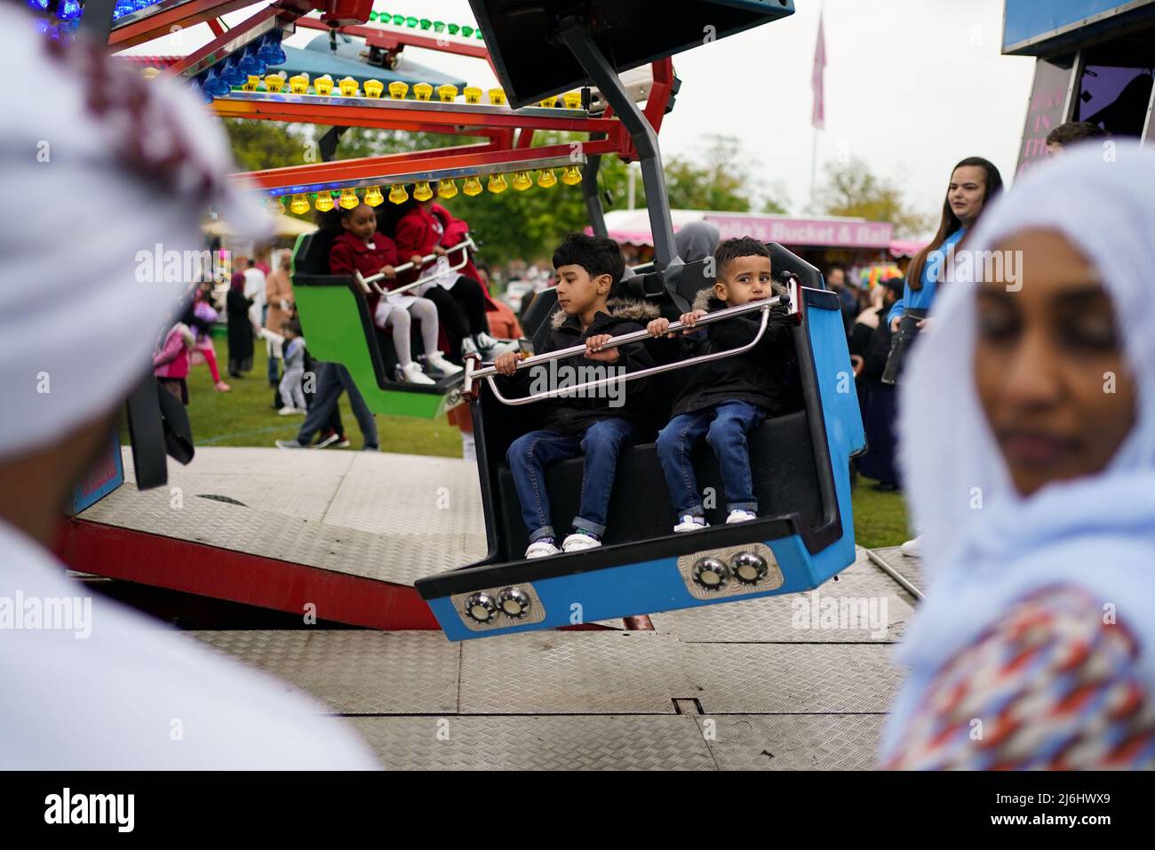 People enjoy theme park rides at a funfair at Small Heath Park in ...