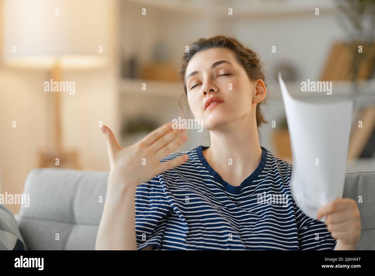 Portrait of beautiful woman fanning herself and restling at home Stock ...