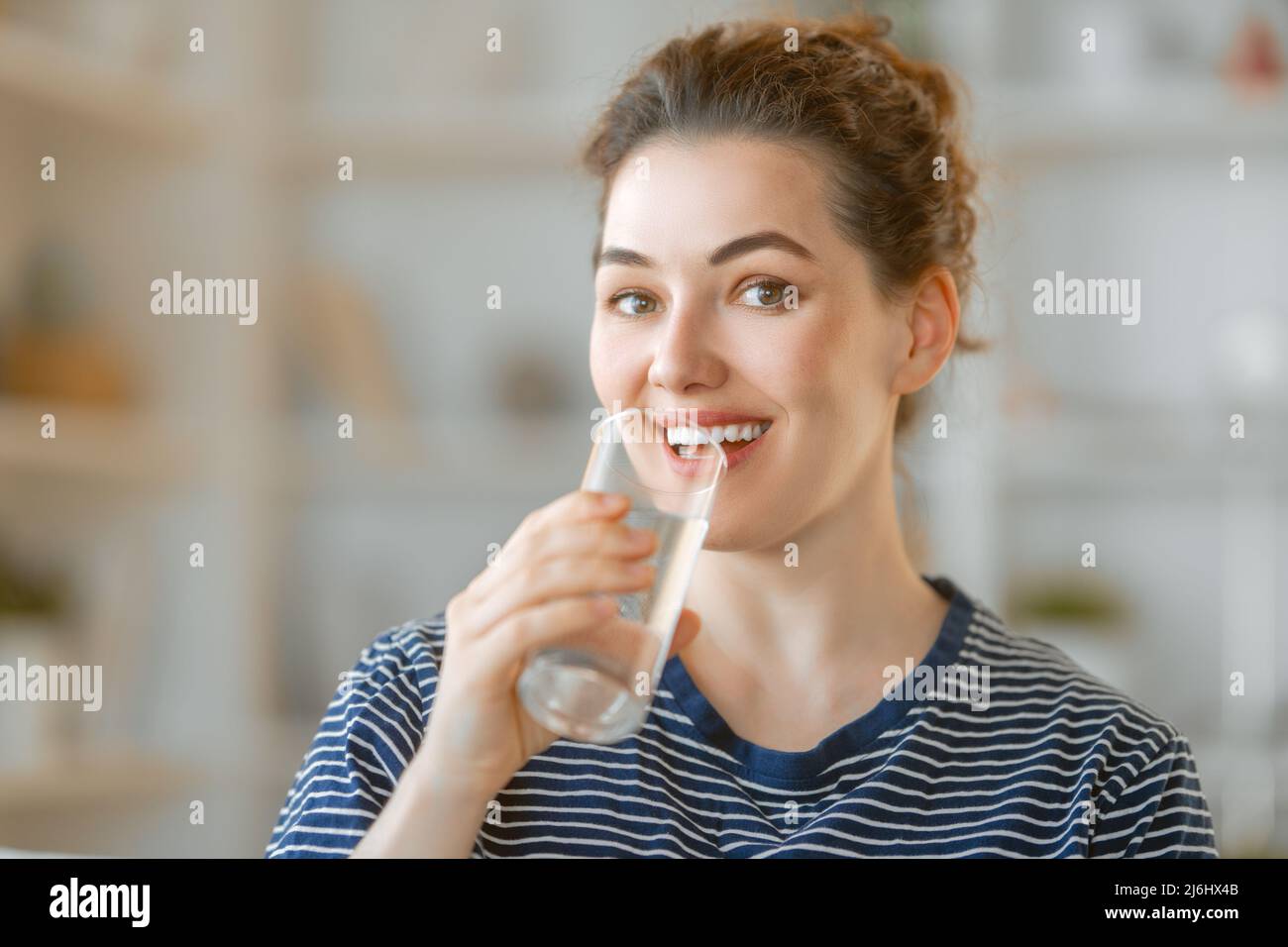 Portrait of beautiful woman drinking pure water and restling at home ...