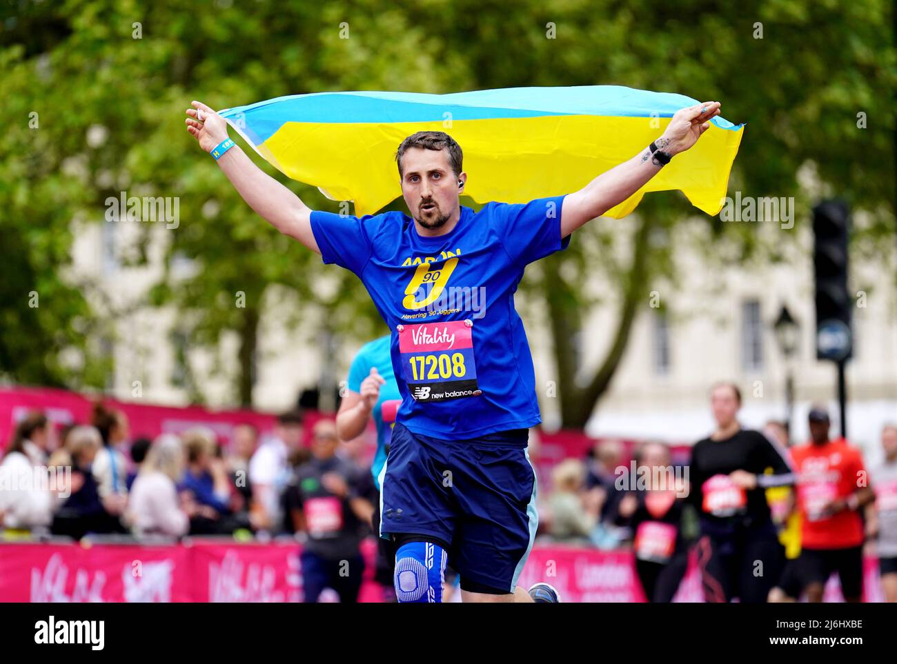 A runner holds up the Ukrainian flag as they compete in the Run For ...