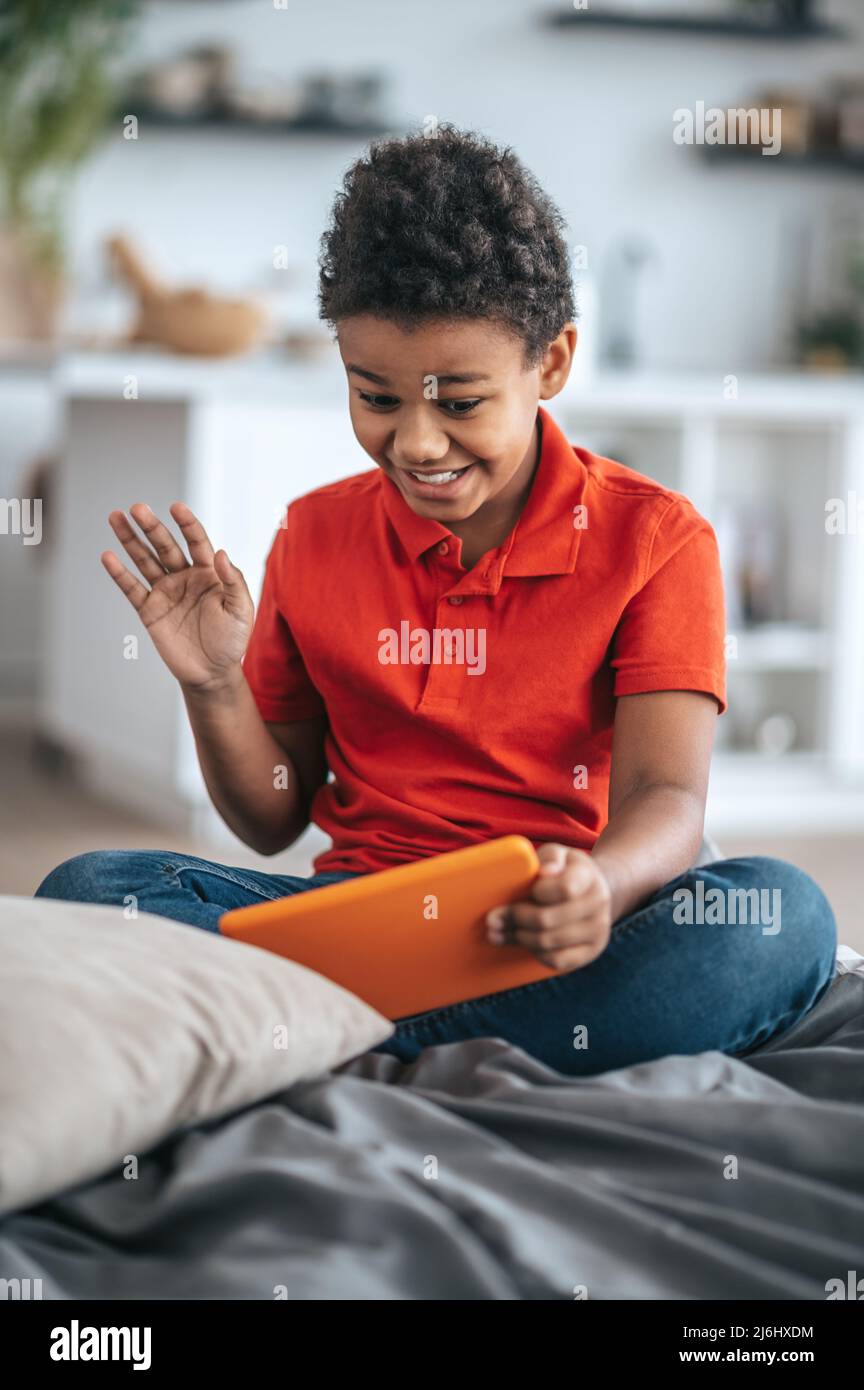 Boy in orange tshirt looking excited while watching something online ...