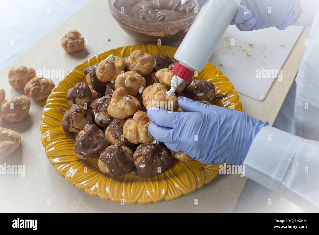 Preparation of profiteroles with cream and chocolate. Filling with ...