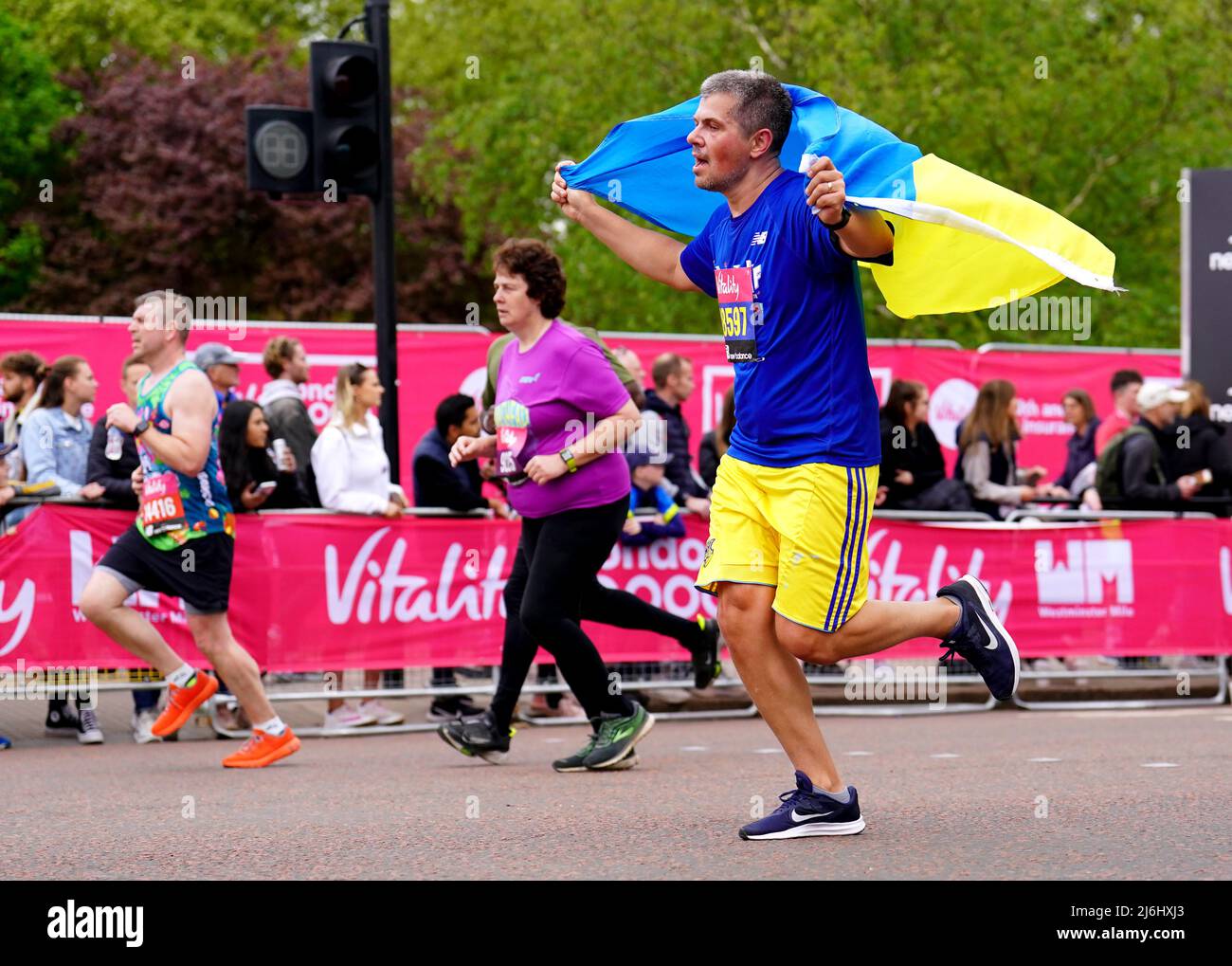 A runner holds up the Ukrainian flag as they compete in the Run For ...