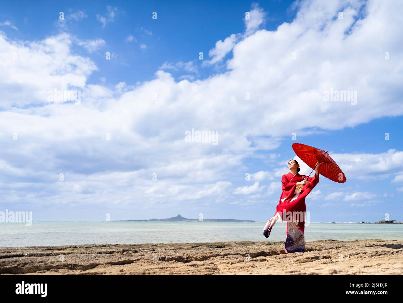 Woman with red Japanese wagasa umbrella and kimono on the beach in ...
