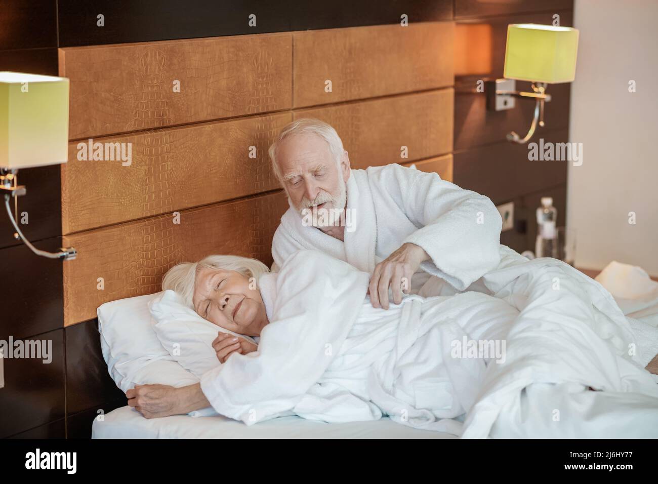 A gray-haired man looking with tenderness at his wife while she ...