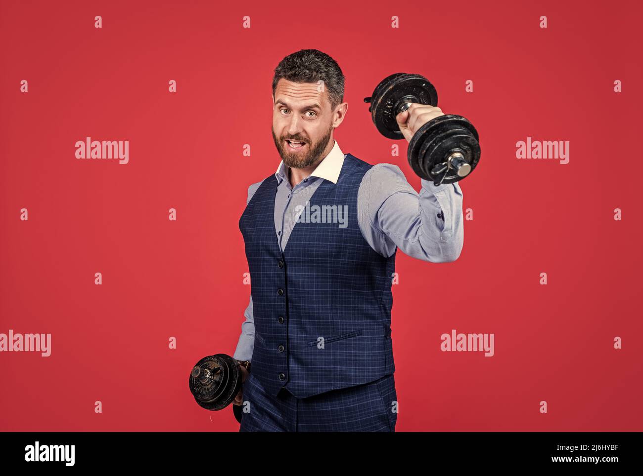 Strong man businessman do dumbbell workout red background, business ...