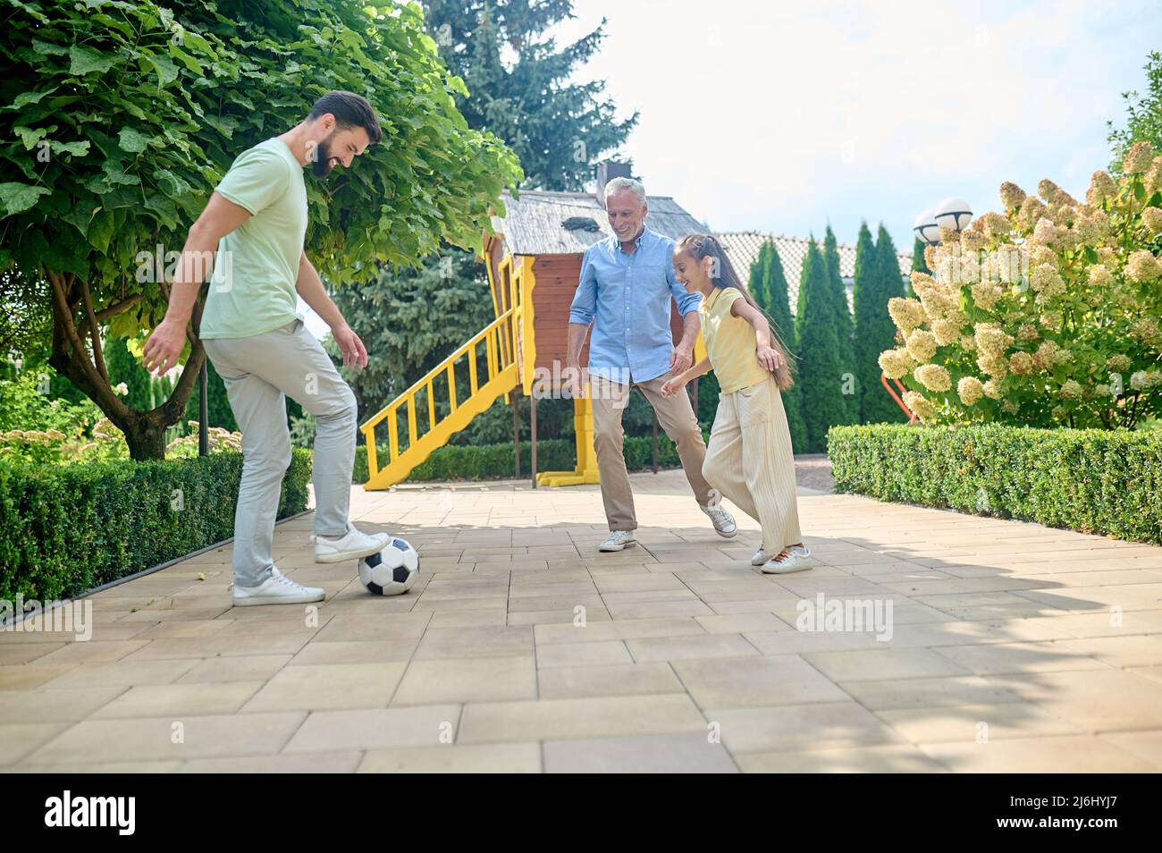 Family playing football in the park and looking involved Stock Photo ...