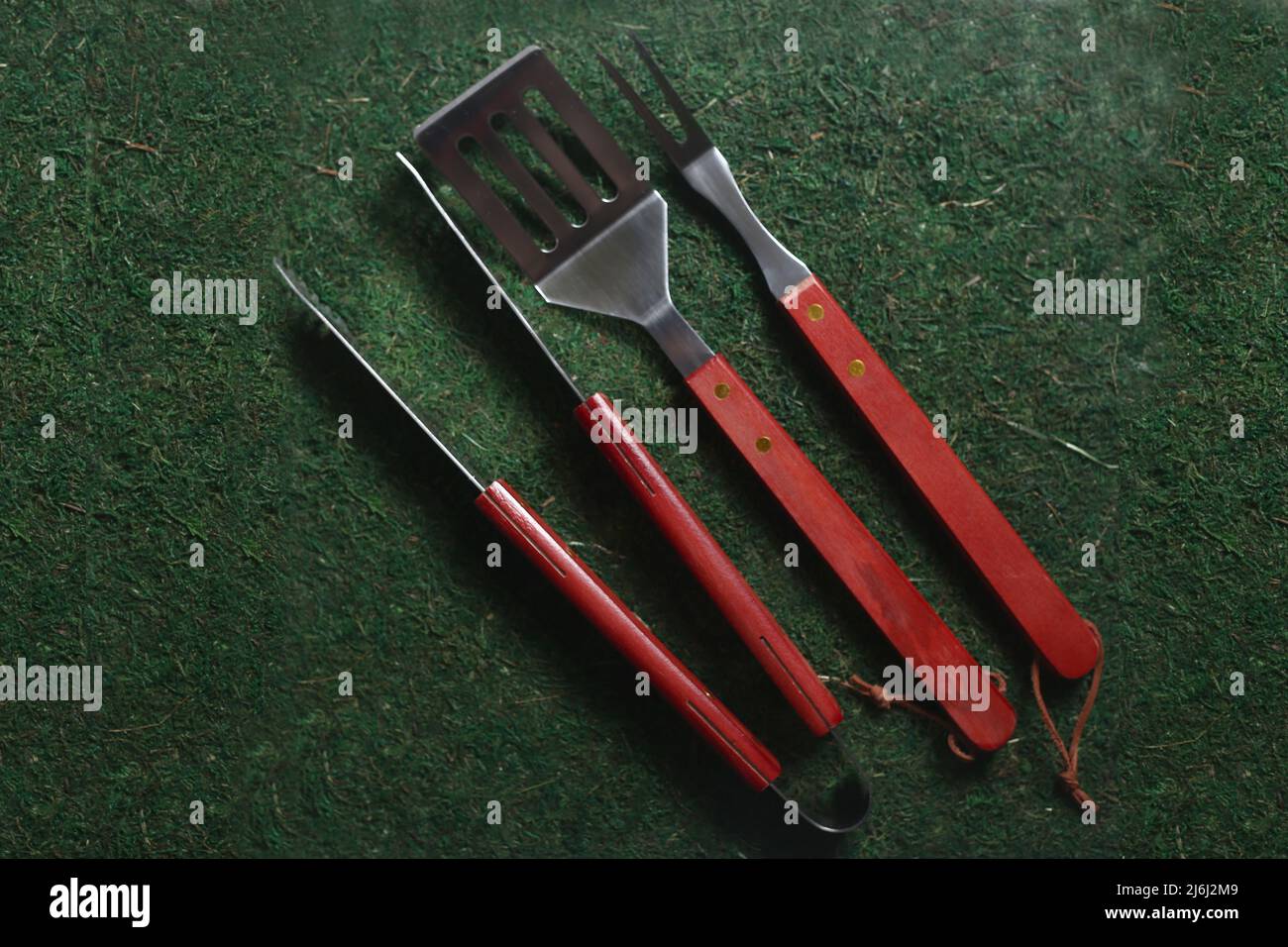 BBQ instruments kit - tongs, spatula, fork - close up isolated on green ...