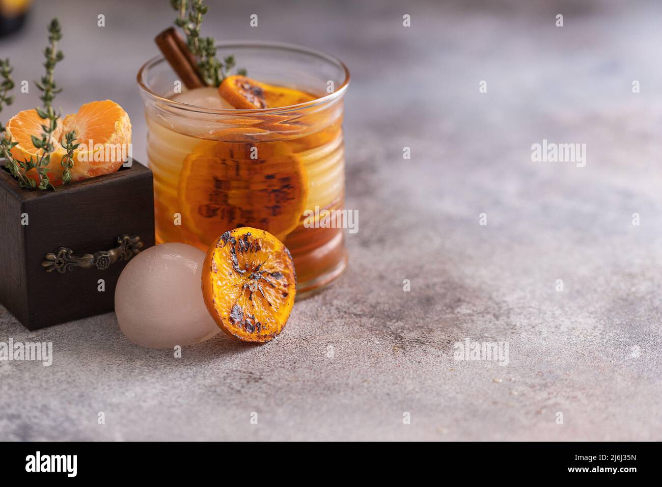 Whiskey sour cocktail with tangerine slices and ice cubes decorated ...
