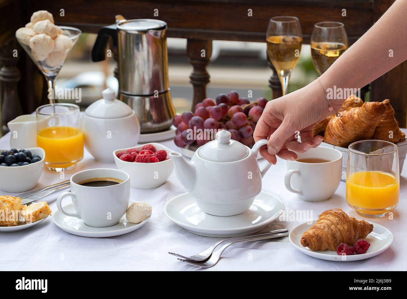 Woman hand holding teapot for making tea on hotel terrace. Luxury ...