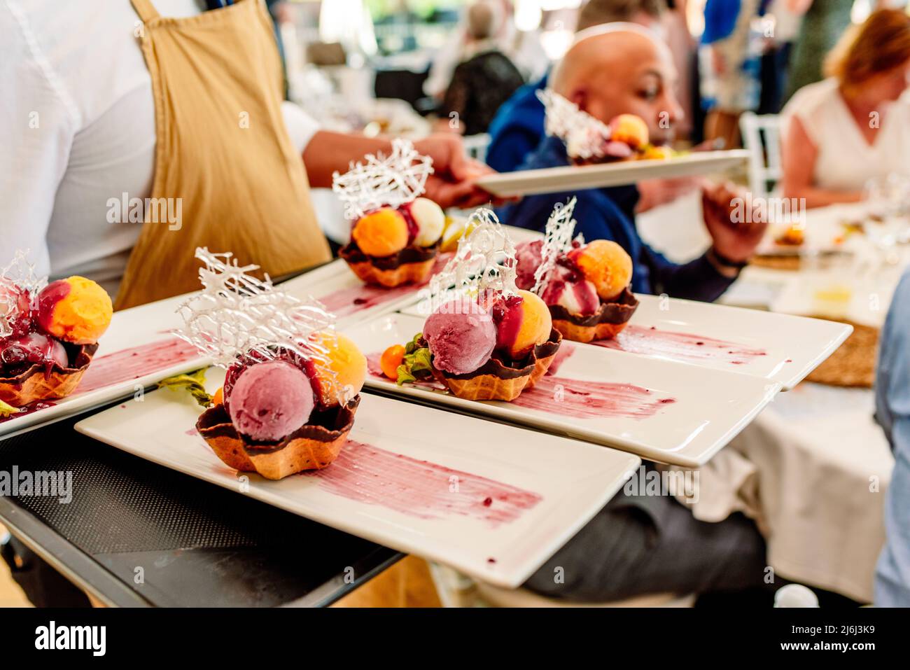 Waiter serves desserts on a tray, ice creams and cakes with delicate ...
