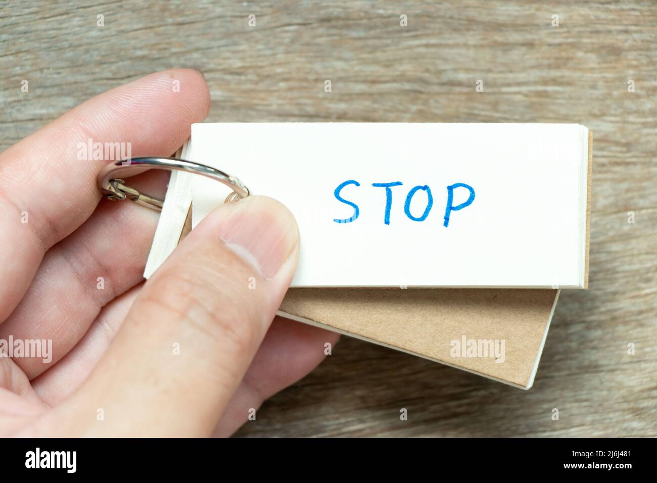 Man hold the flash card with handwriting word stop on wood background ...