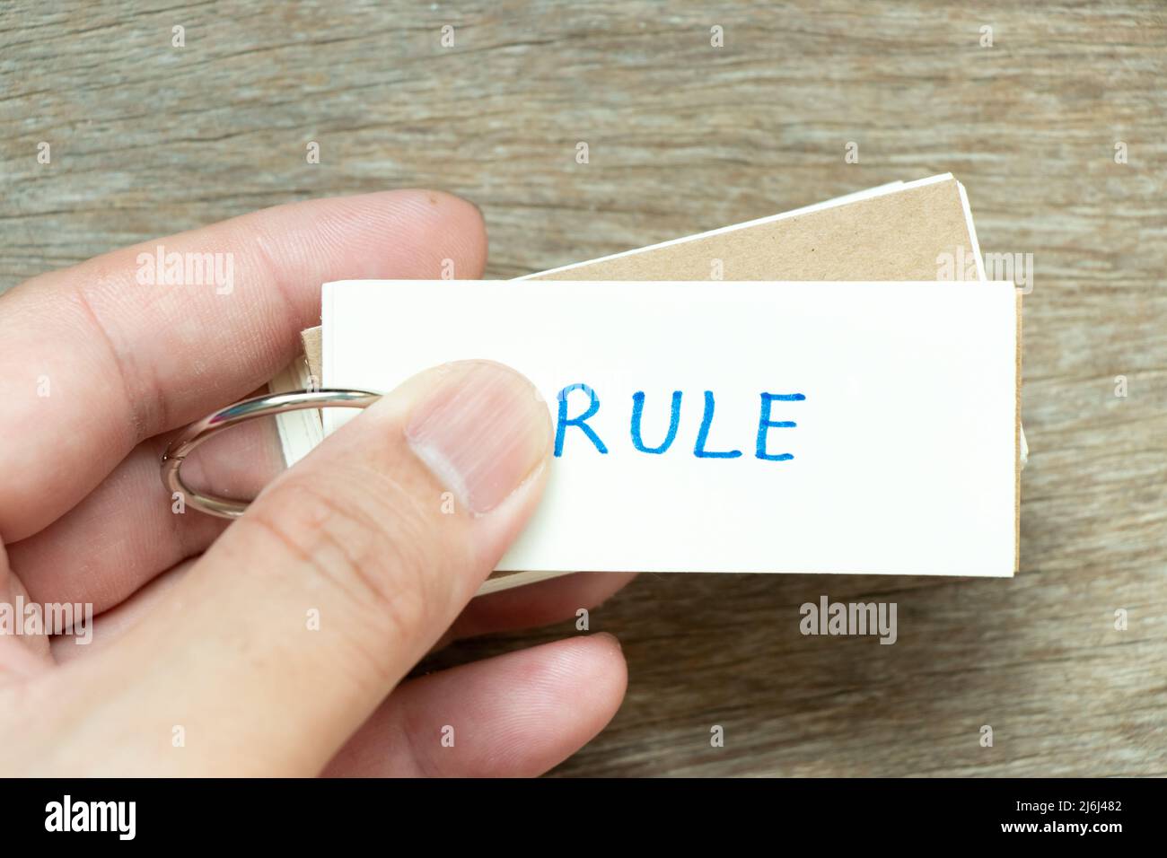 Man hold the flash card with handwriting word rule on wood background ...