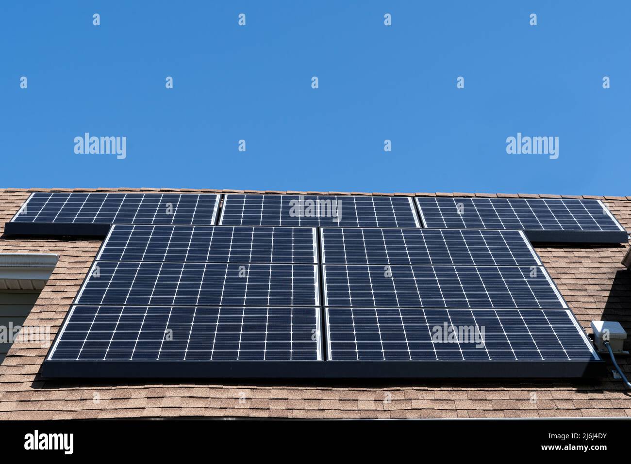 A residential solar panel array mounted on an asphalt shingle roof with ...