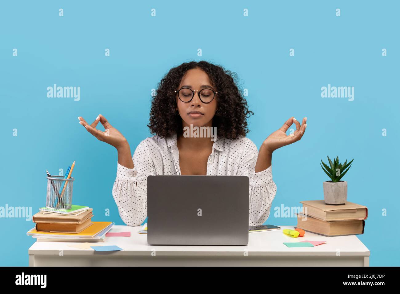 Workplace stress management. Calm young black woman meditating in front ...