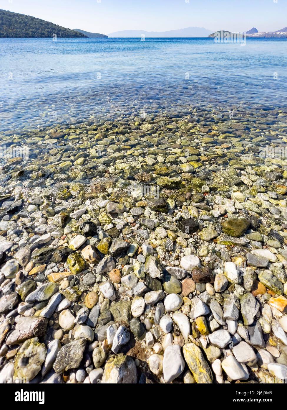 Close-up of wet stones and sea. Pebble beach. Tiny rocks in crystal ...
