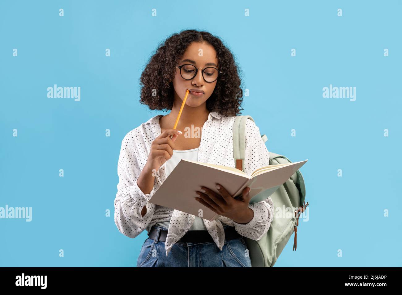Thoughtful African American female student reading book, thinking over ...