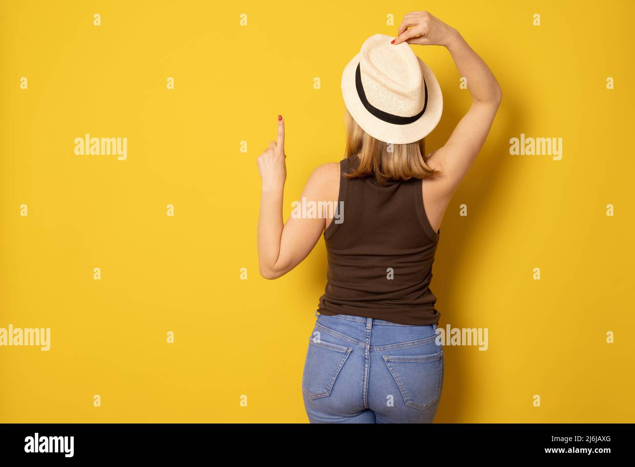 Back view young woman wearing straw summer hat put hand on head ...