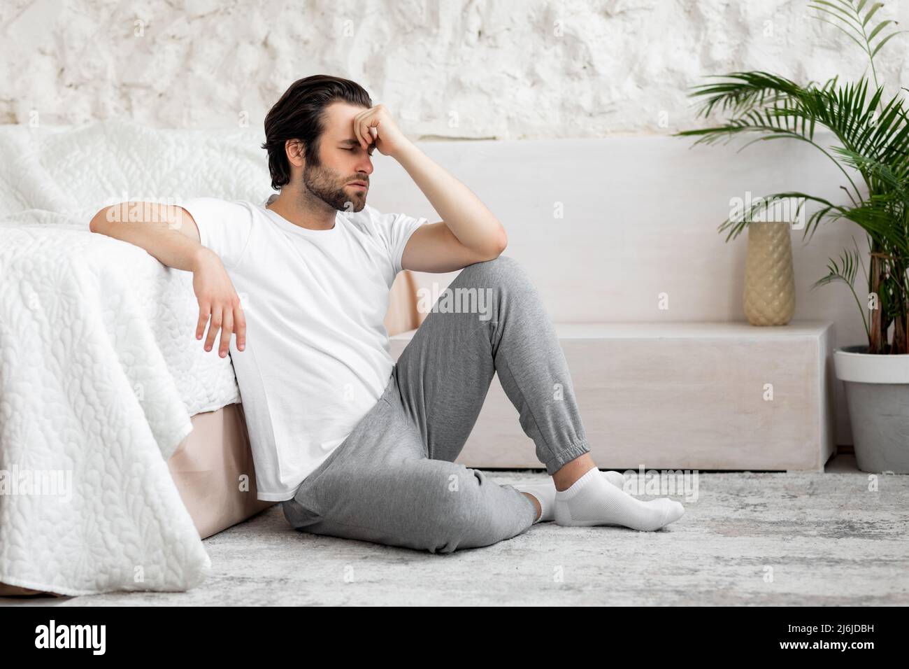 Grumpy millennial man feeling down, bedroom interior Stock Photo - Alamy