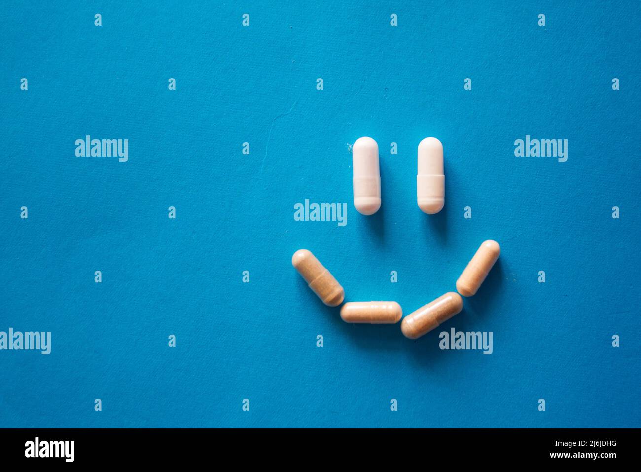 Happy smile from tablets on blue background Stock Photo - Alamy