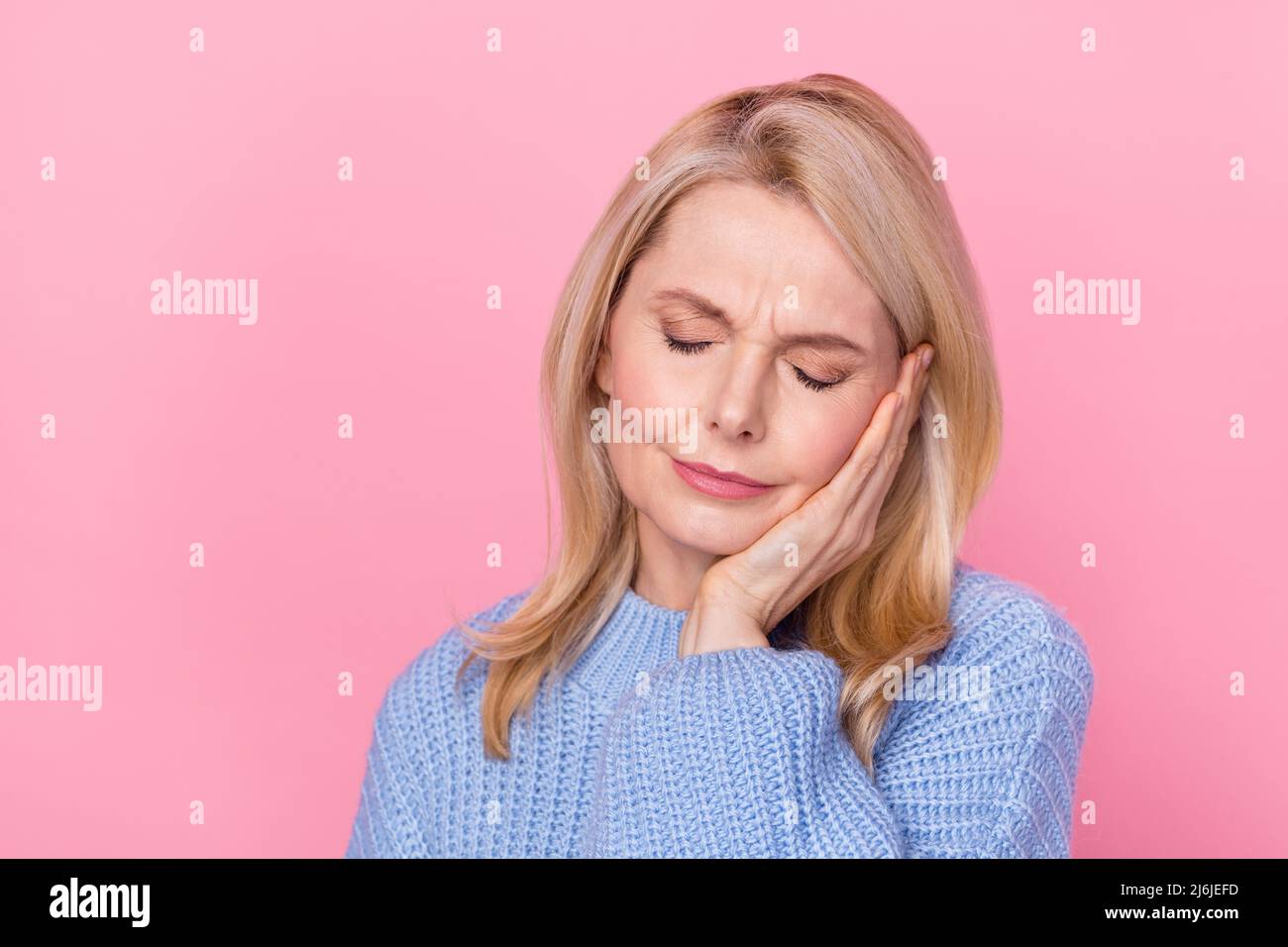 Photo of pain mature blond lady hand cheek wear blue sweater isolated ...