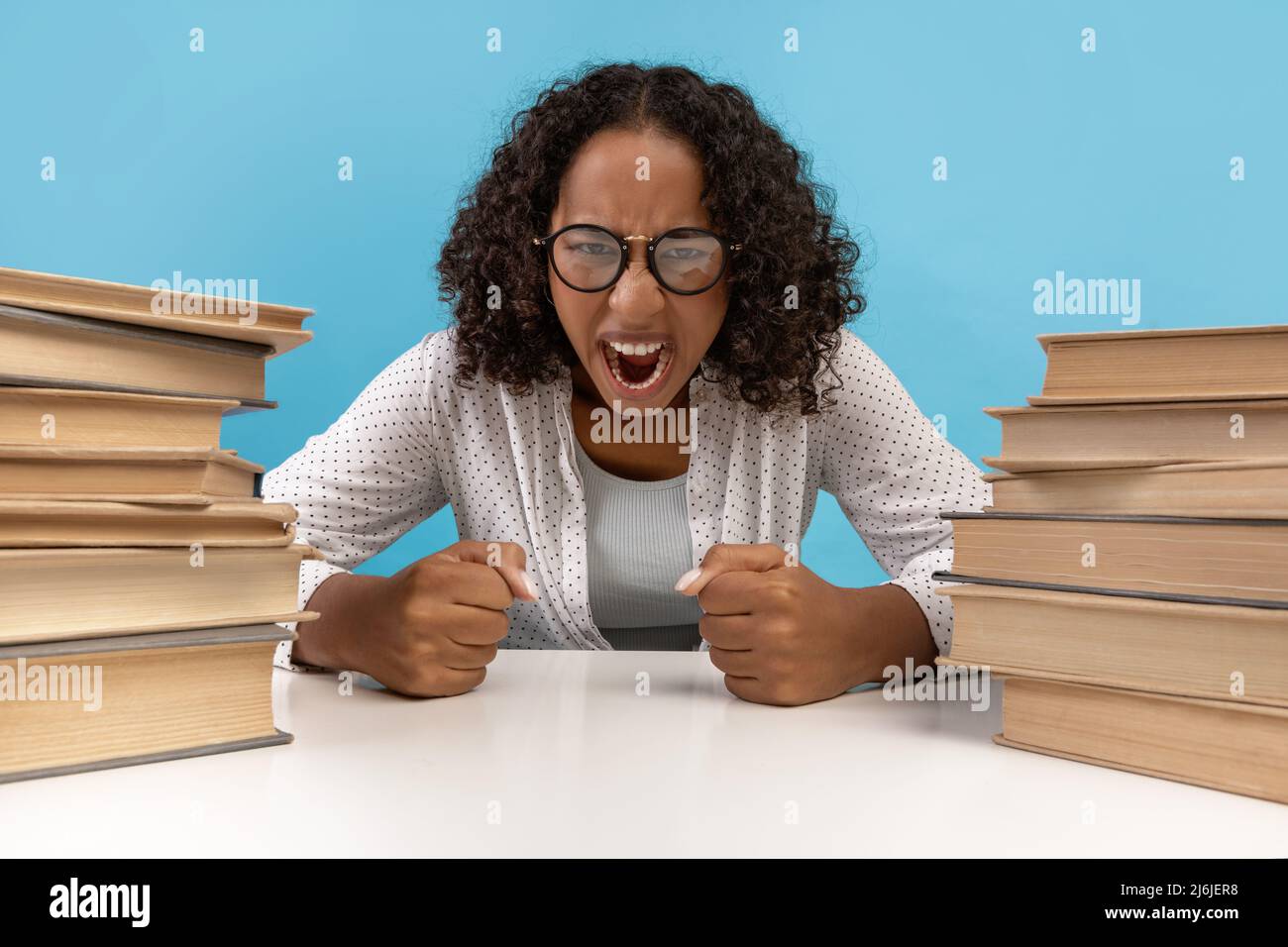 Angry African American female student with heaps of books shouting and ...