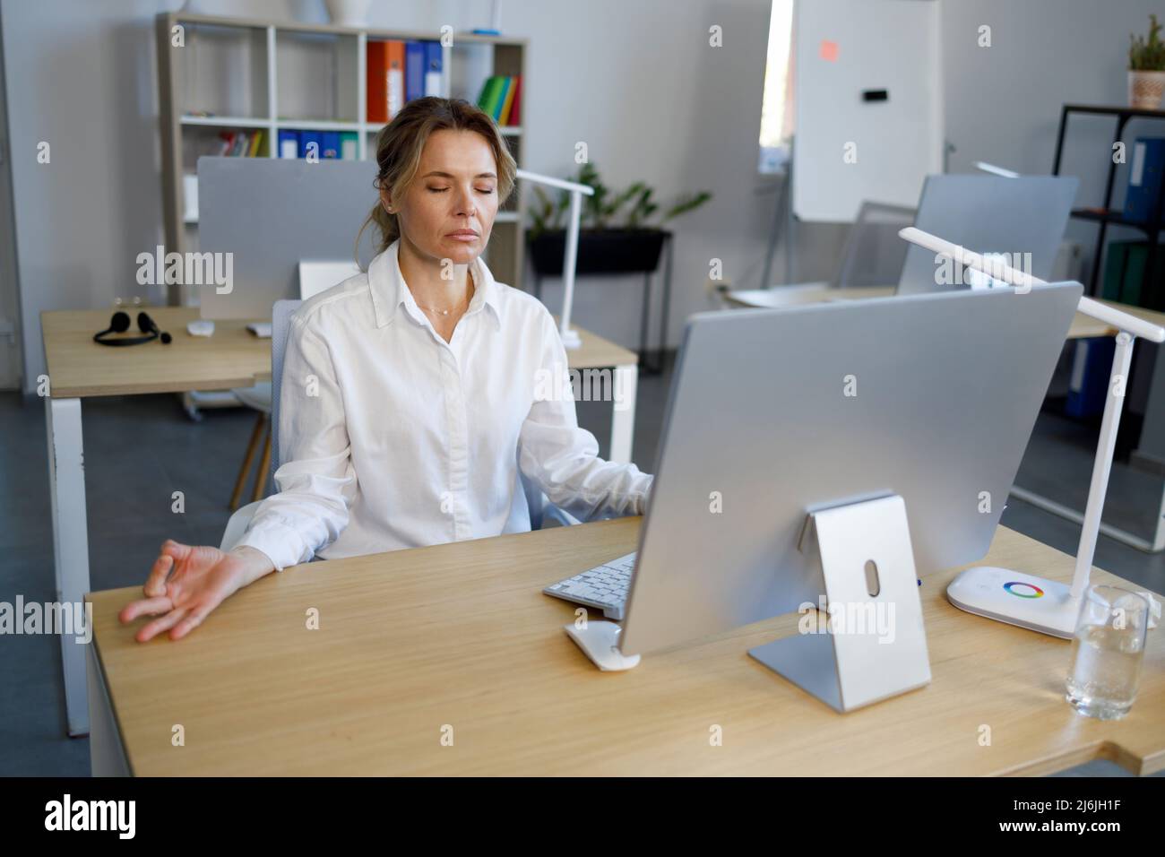 Calm businesswoman meditating at office desk with eyes closed Stock ...