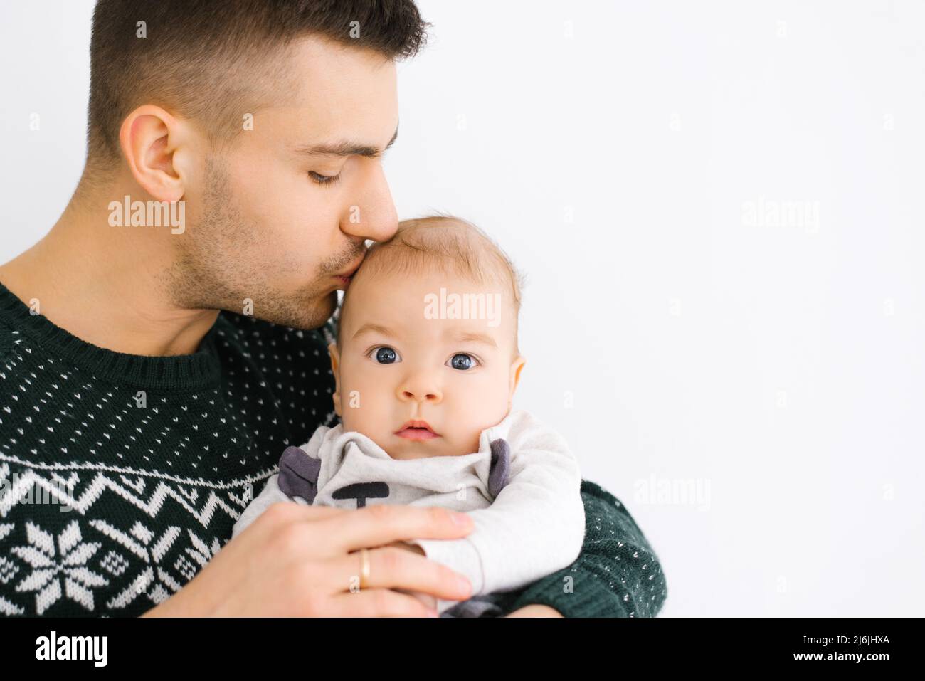 A young father holds his little son in his arms and kisses him on a ...