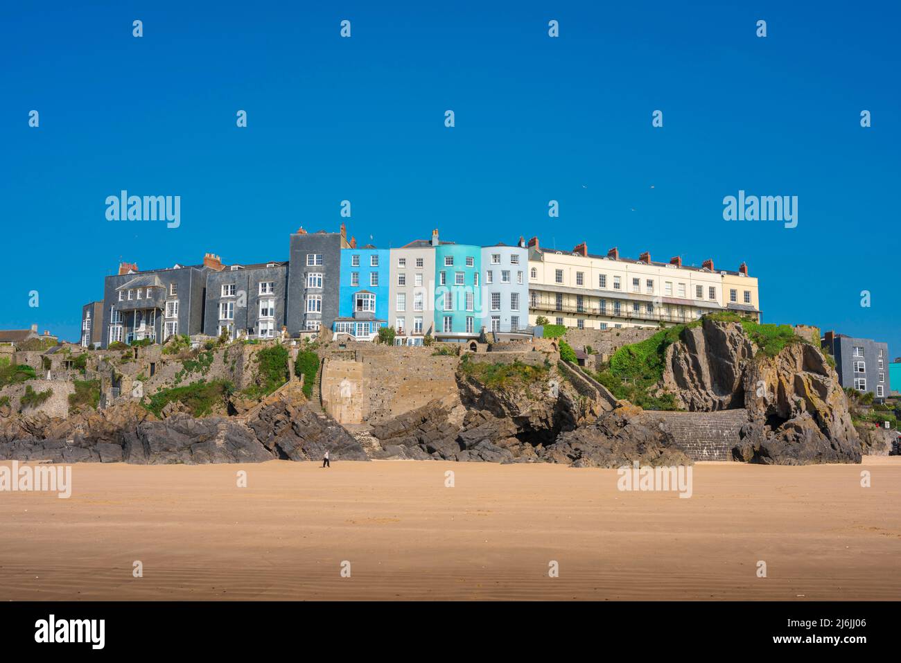 Tenby South Beach, view in summer of people walking beneath colourful ...