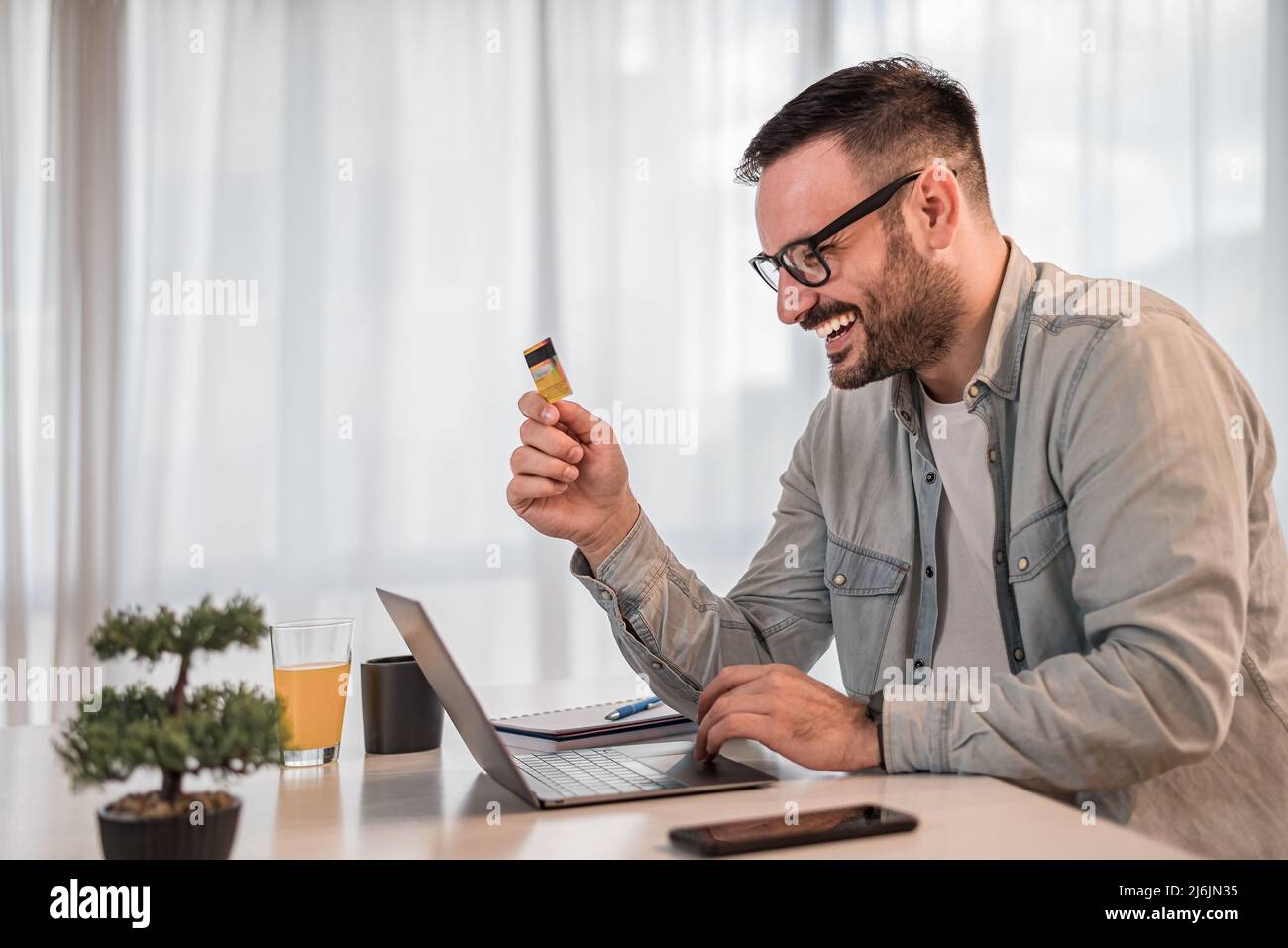 Cheerful businessman with credit card checking online transaction. Male ...