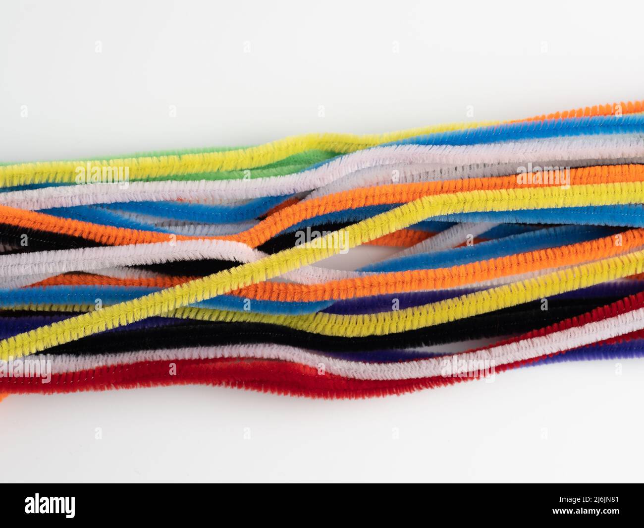 A quantity of Neon rainbow colored pipe cleaners on a white background ...