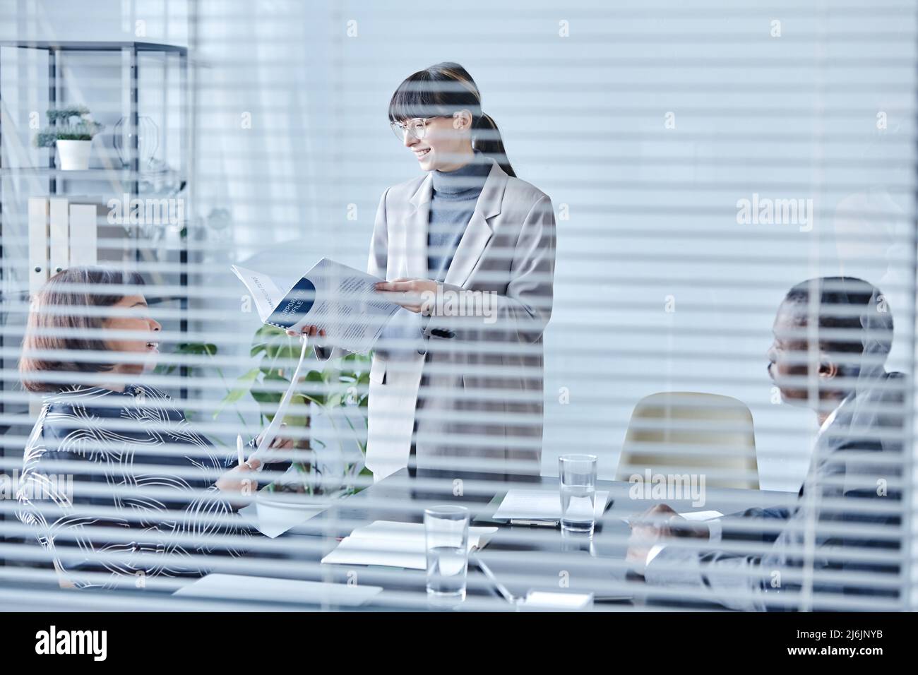 Portrait of young woman executive talking to team in business meeting ...