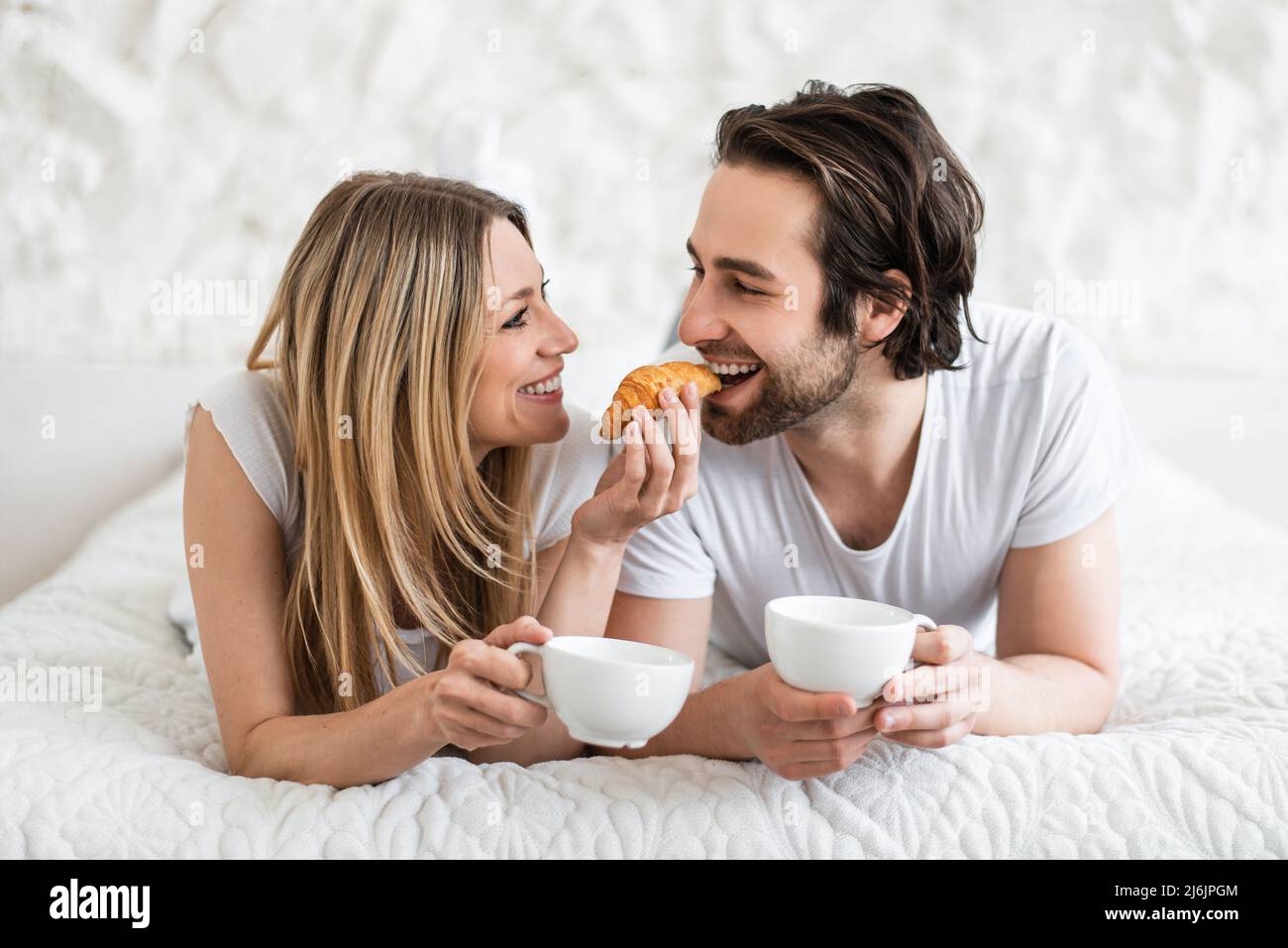 Loving Young Couple Eating Breakfast And Drinking Coffee In Bed At Home