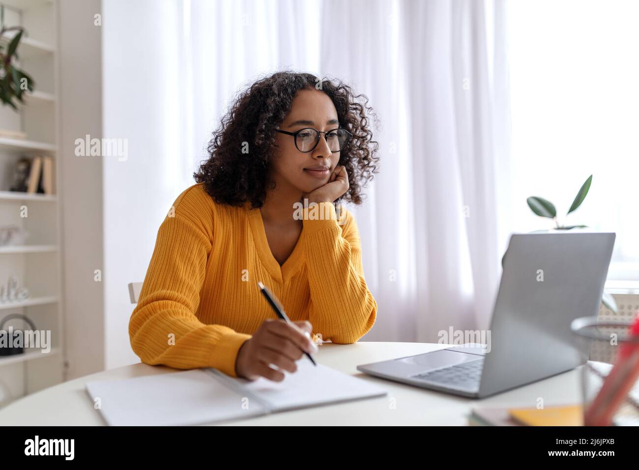 Positive young black female student having online lesson on laptop ...