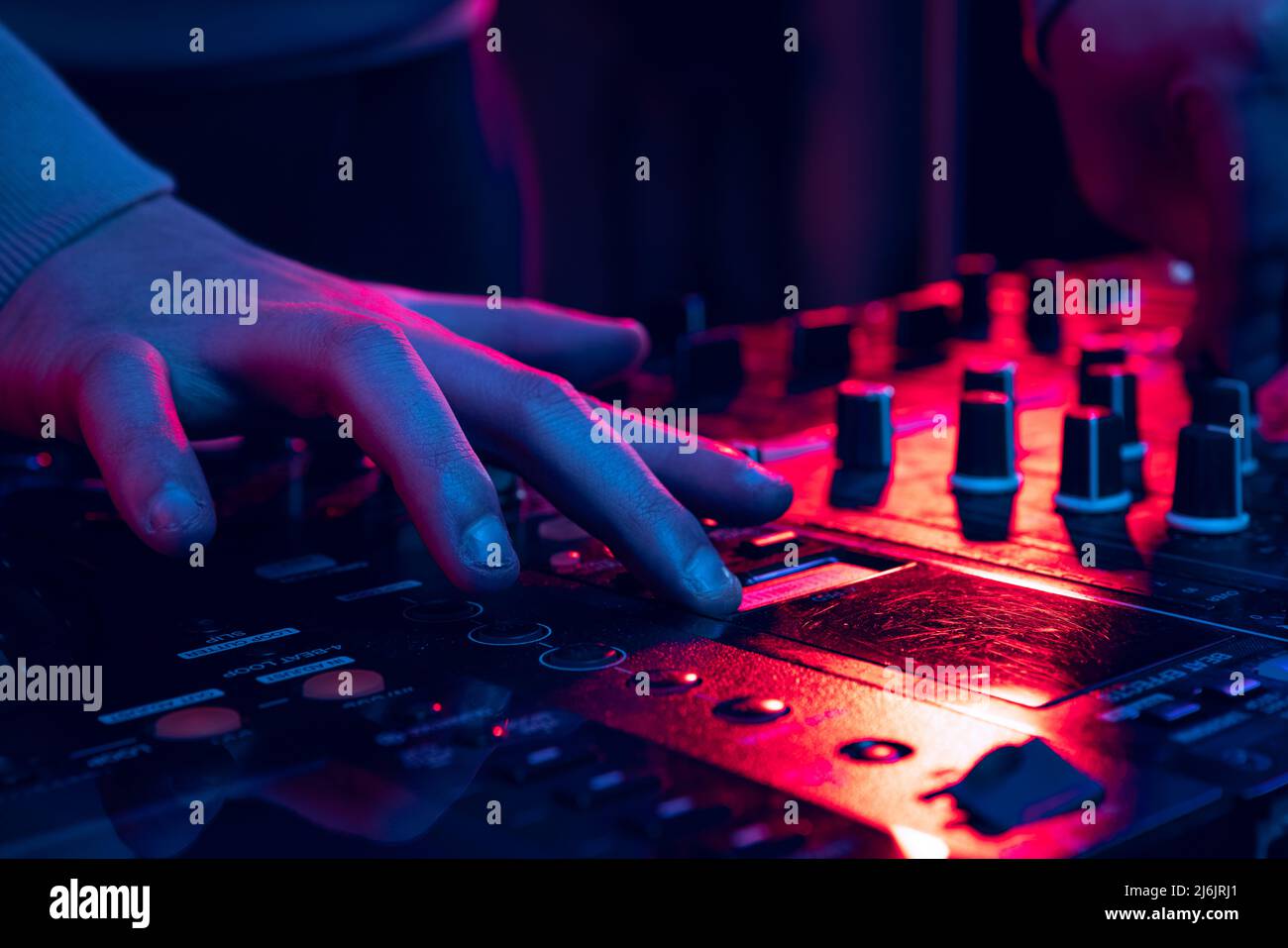 Close-up image in neon lights. Male hands turning sounds on ...