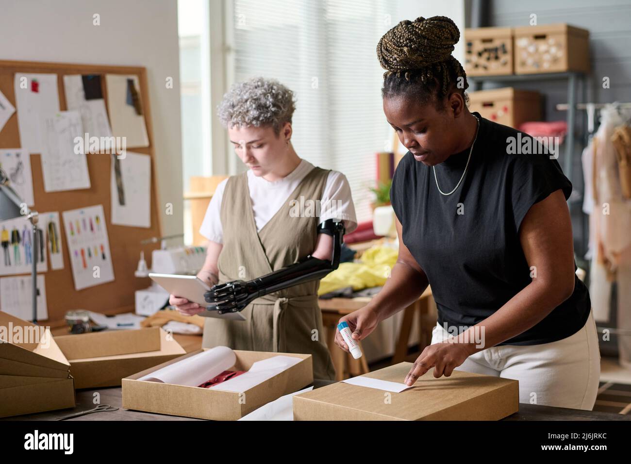 Black woman sticking small paper with receiver address on packed box ...