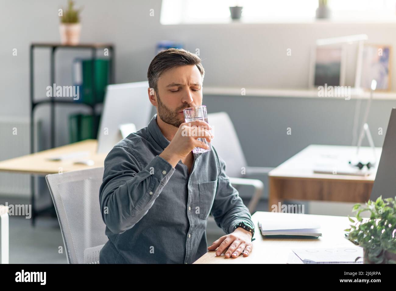 Mature male manager holding glass of water, drinking water while ...